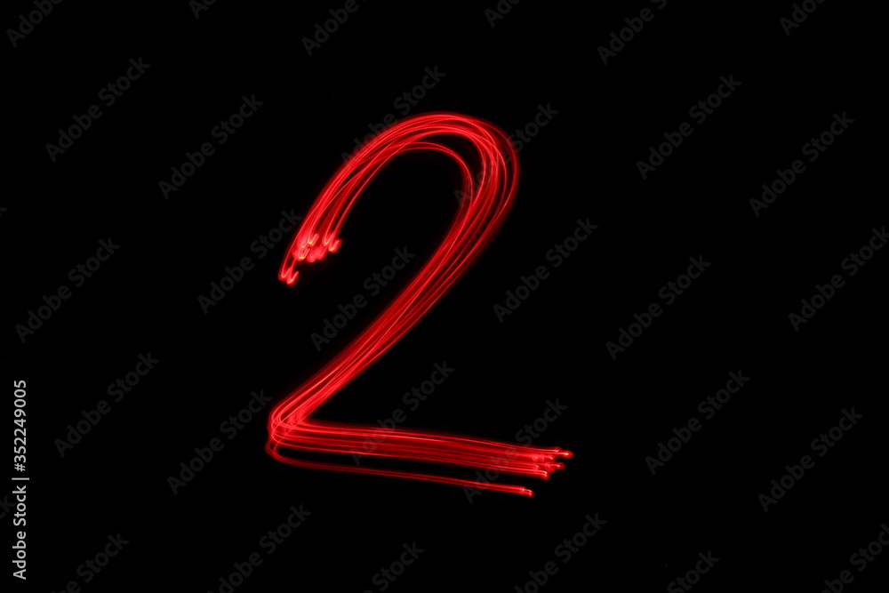 Long exposure photograph of the number 2 in neon red colour fairy ...