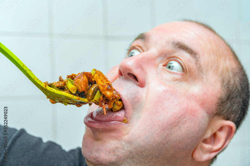 A crazy man with bulging eyes looks at fatty and junk food, sending it ...