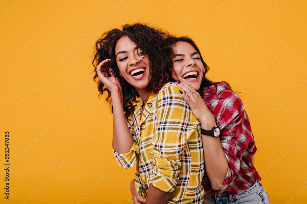 Girls in stylish street clothes sincerely laugh at each other's jokes ...