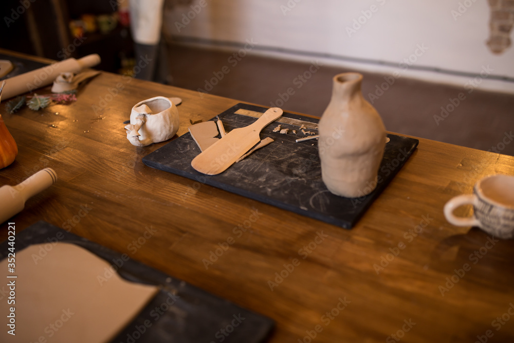 A master class in modeling a clay jug. Table with clay and a tool for ...