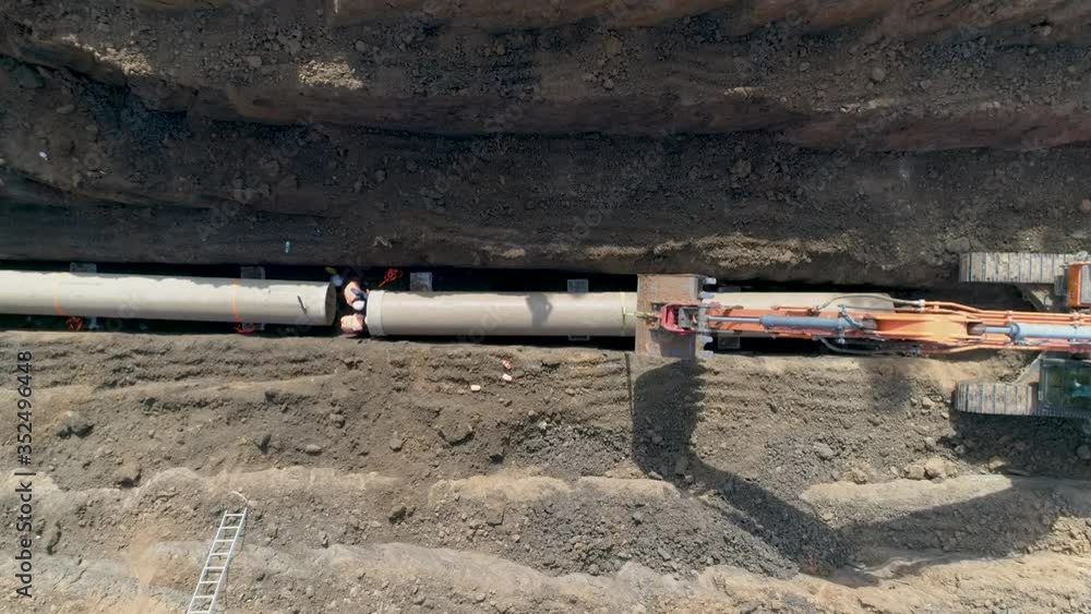 Tractor digging in sand soil ground to laying installing water pipeline ...