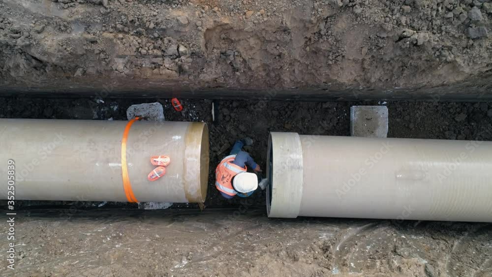 Concrete pipe tube installation. Aerial above men at work outside with ...