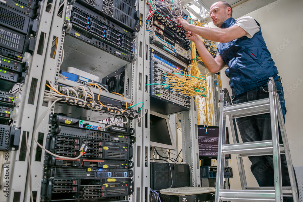 Technician standing on a ladder connects internet wires. The specialist ...