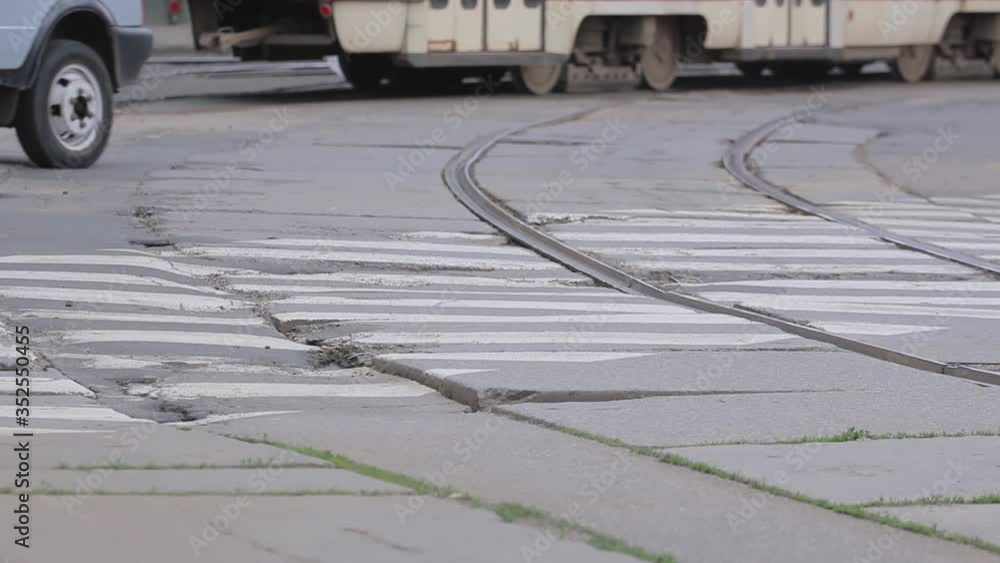 Poor condition of the road surface with tramway rails. Cars crossing ...