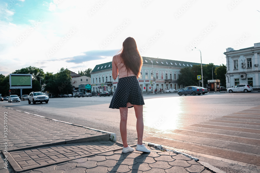 a person stands at a pedestrian crossing in a large city and drivers do ...