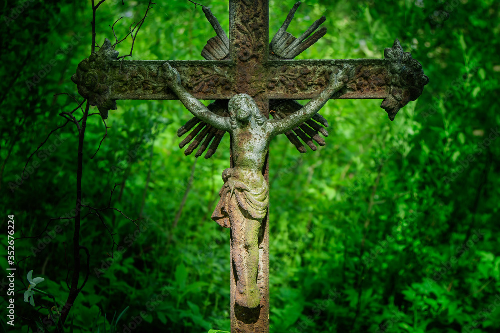 Ancient iron statue of the crucifixion of Jesus Christ against green ...