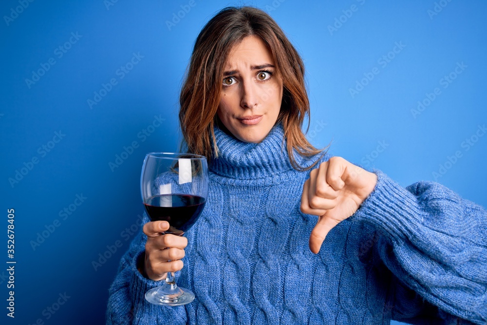 Young beautiful brunette woman drinking glass of red wine over isolated ...