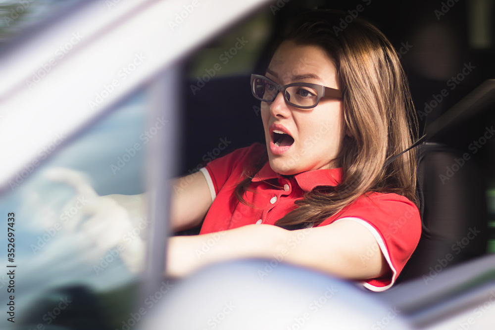 frightened girl driving a car in shock. dangerous situation on the road ...