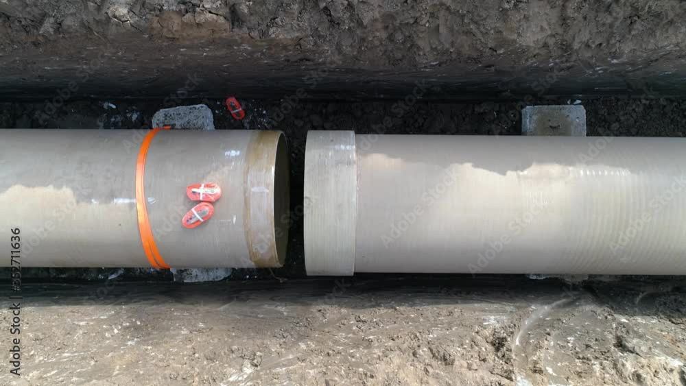 Concrete pipe tube installation. Aerial above men at work outside with ...