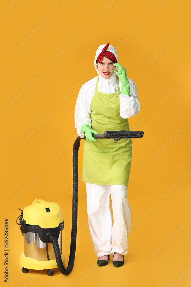 Housewife in protective costume and with vacuum cleaner on color ...