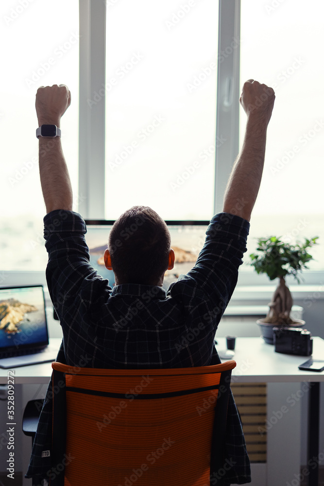 Back view portrait of a successful man, who is celebrating at his work ...