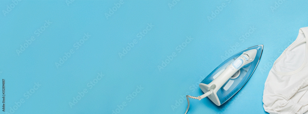 Iron for ironing things and a white T-shirt on a blue background ...