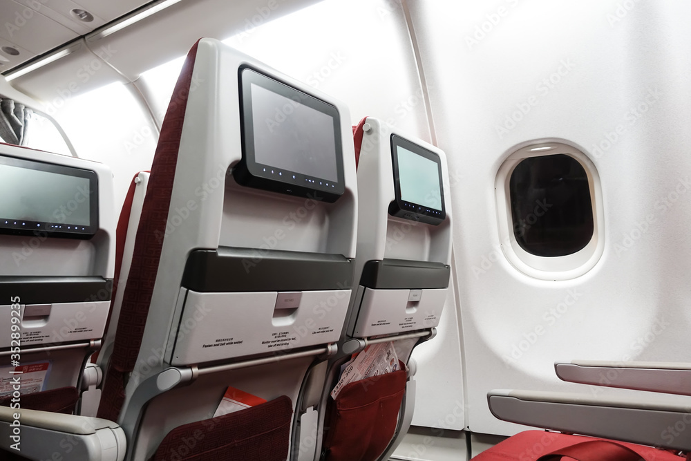 airplane seat with screen beside window with sun light Stock Photo ...