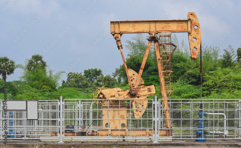 Old rusty oil pump jack extracting crude oil and natural gas from an ...
