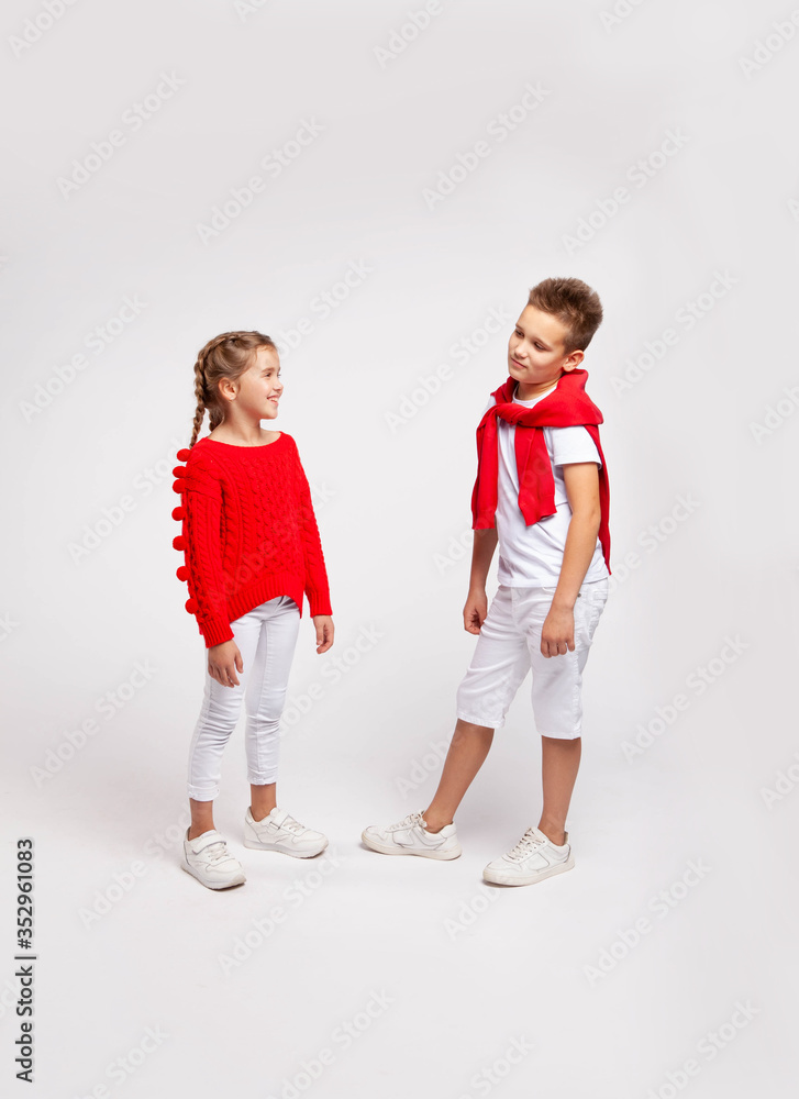 A boy and a girl stand apart from each other. The boy looks in ...