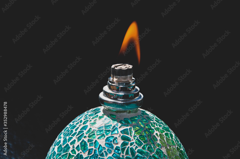 Ignited catalytic turquoise lamp against the black background. Flame ...
