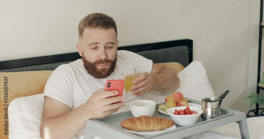 Bearded young man choking on while drinking juice and reading shocking ...