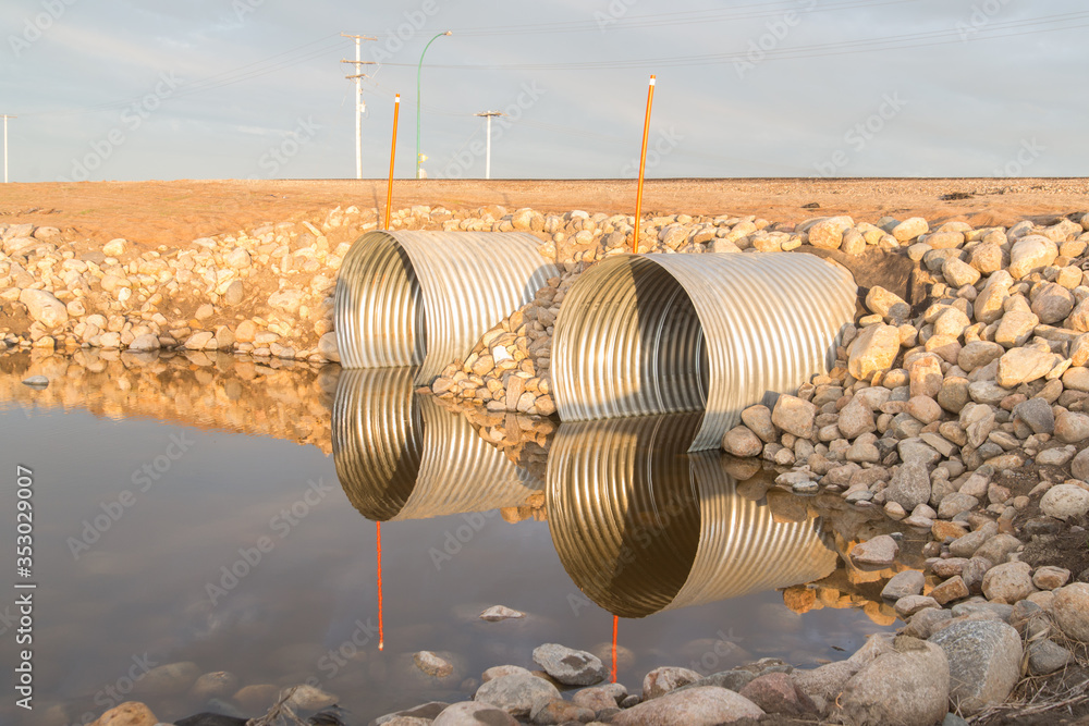 two steel culverts reflecting in water surrounded by rocks Stock Photo ...