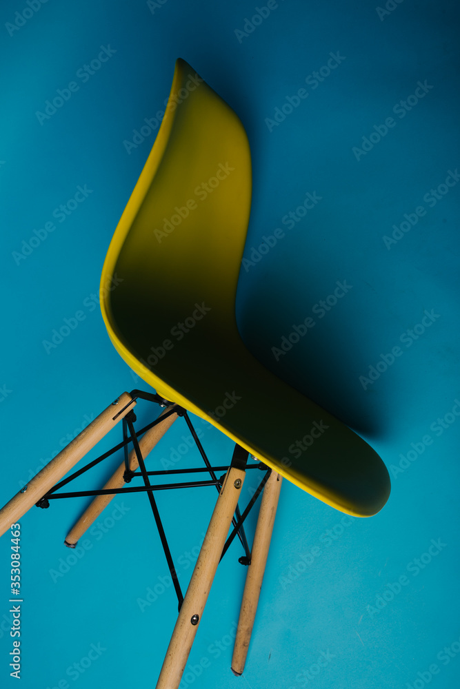 yellow chair on a blue paper background. concept: an interior element ...