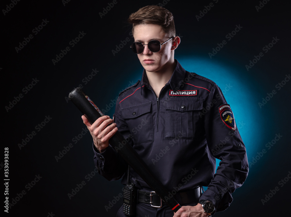handsome guy in a police officer's uniform with a baseball bat. english ...