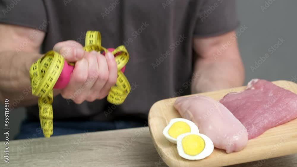 Healthy eating concept. Man of athletic build eats healthy food high in ...