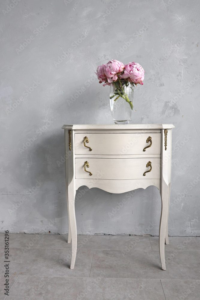 Room interior with bedside table on the gray loft wall. Glass vase with ...
