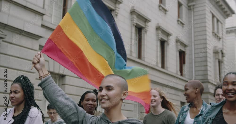 Happy young people with rainbow flag attending a gay parade. Group of ...