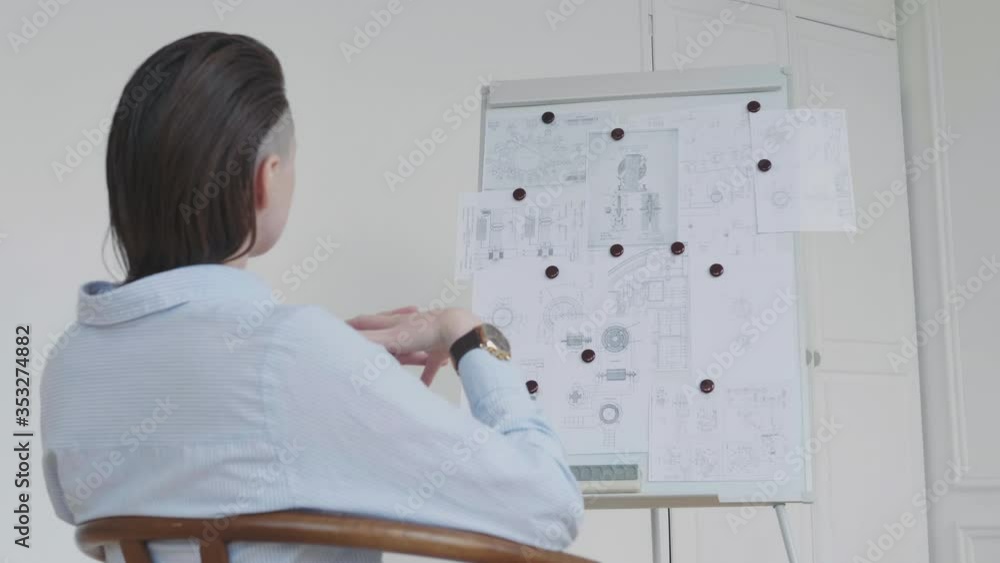 The girl looks wistfully at the drawings. Flipchart with drawings. The ...