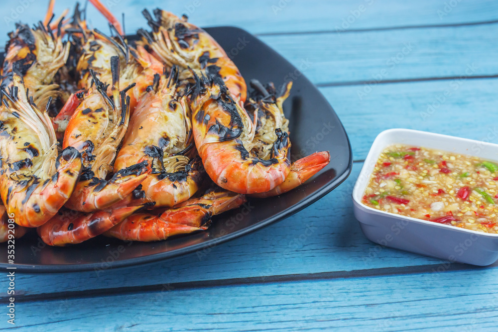 Many fresh river prawns grilled with seafood sauce Placed on blue wood ...