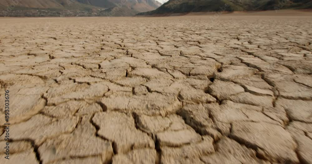 Dynamic shot of cracked soil ground of dried lake or river in mountains ...