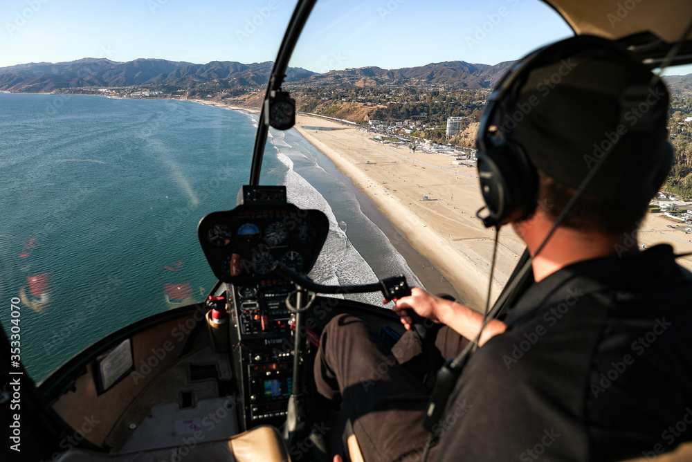 Helicopter cockpit flying on landscape and blue sky, with pilot arm ...