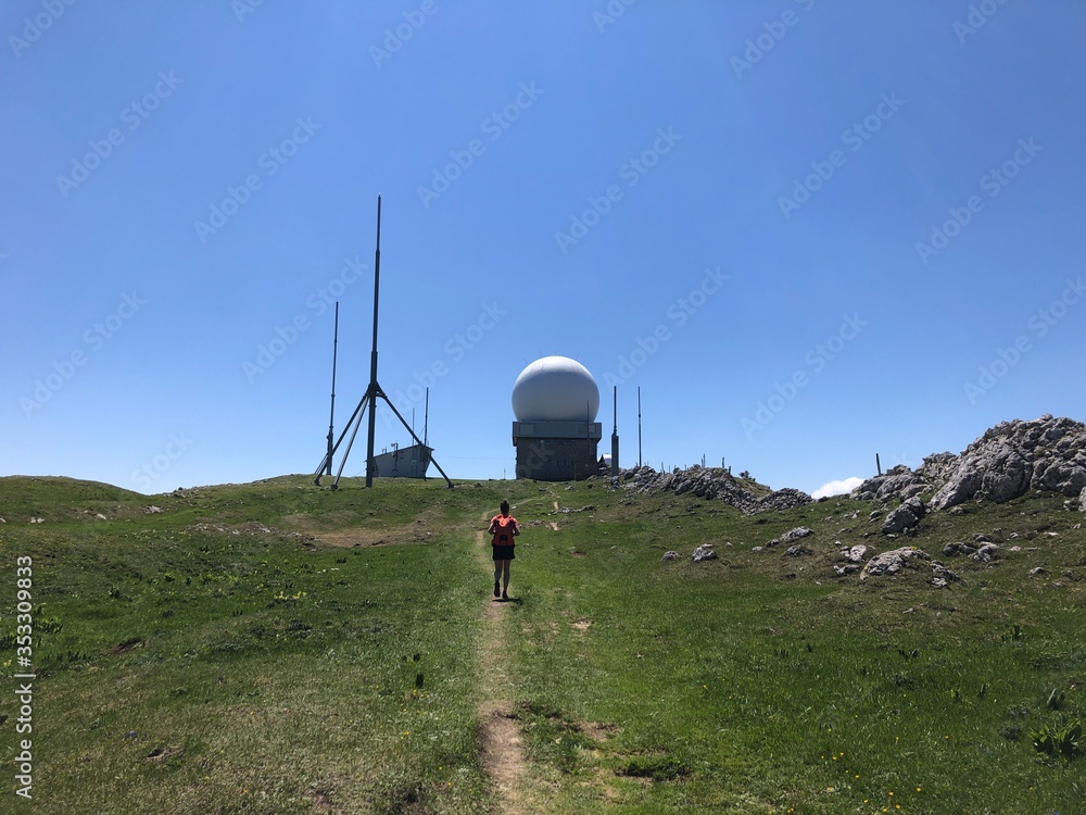 Woman hiking on a path in the grass towards the modern installation, a ...