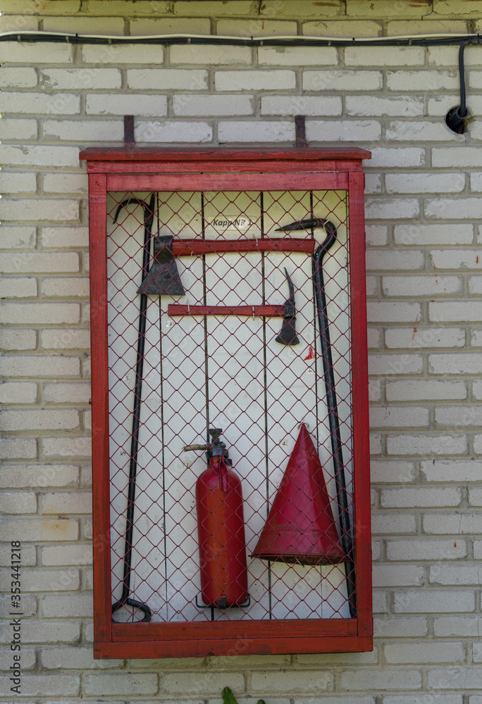 Red wooden cabinet on white brick wall. Firefighter equipment ...