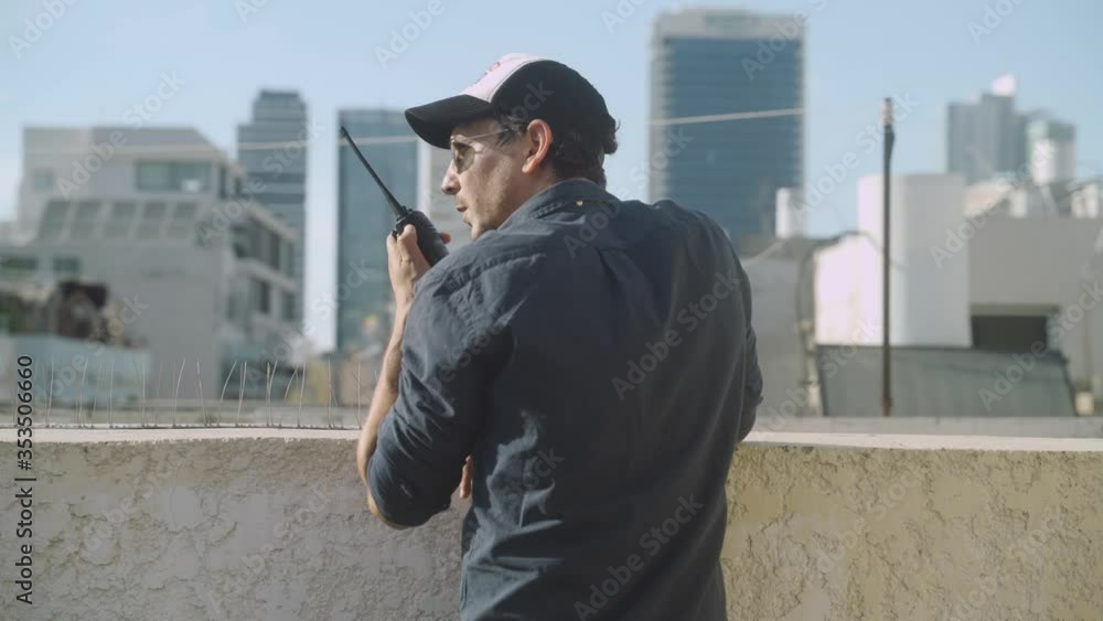 Special agent security guard watching from city rooftop with walkie ...