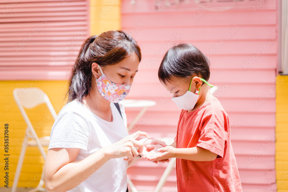 Asian mother clean up her kid hands with alcohol gel or alcohol ...