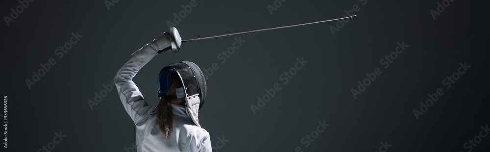 Back view of fencer training with rapier isolated on black, panoramic ...