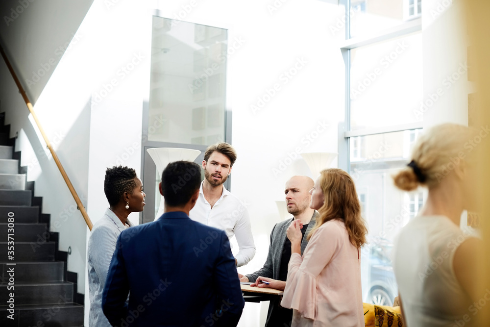 Business people discussing while standing by table in office Stock ...