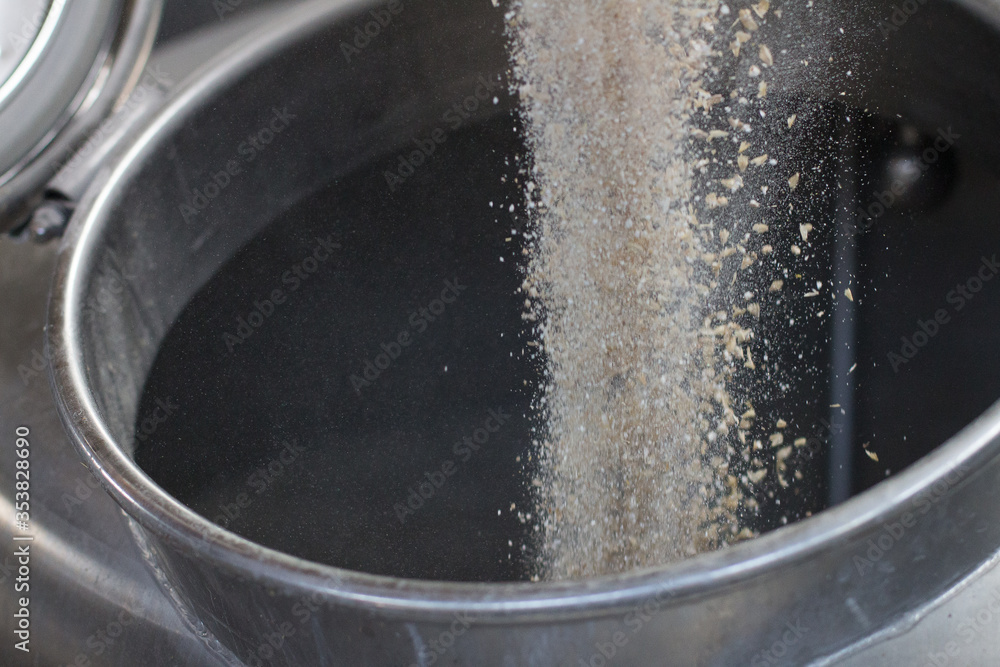 Detail of pouring beer malt into an industrial boiler, inside a brewery ...