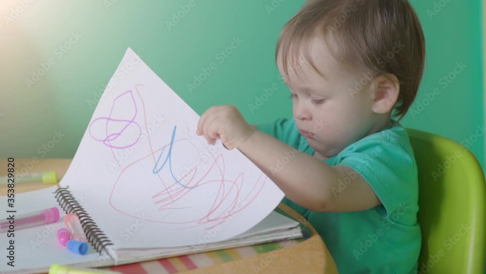Cute adorable little girl drawing with colorful markers on paper album ...