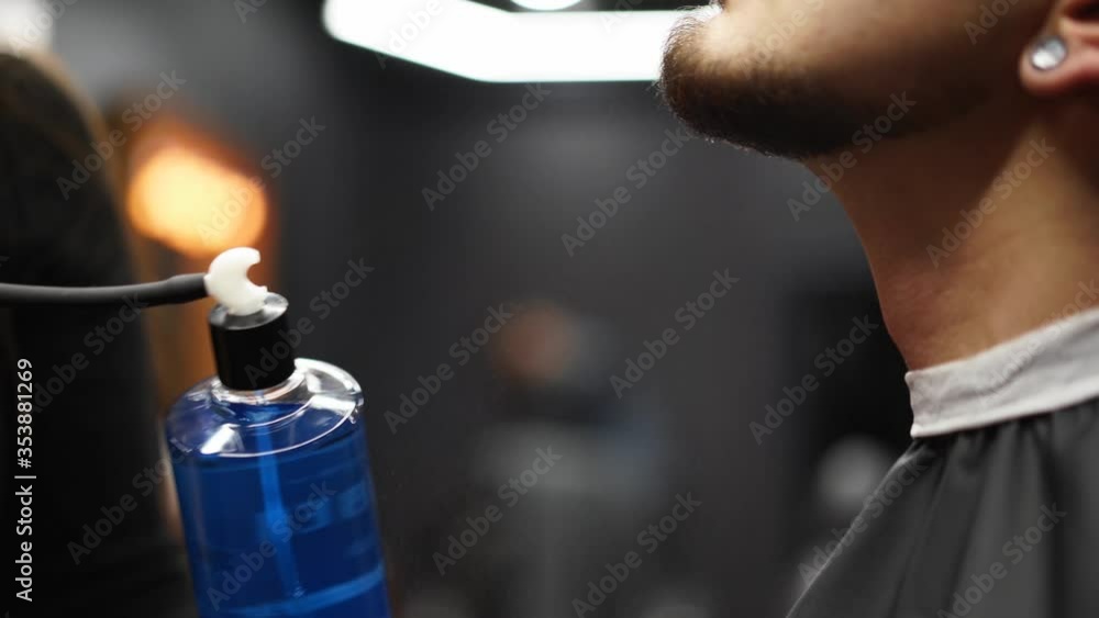 Barber sprays parfume on client in barbershop after haircut and styling ...