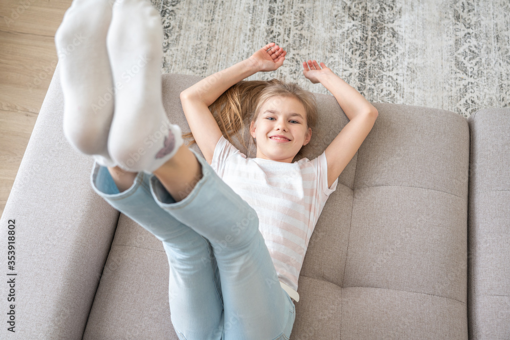 Preteen girl lying on couch with her feet raising up high Stock Photo | Adobe Stock