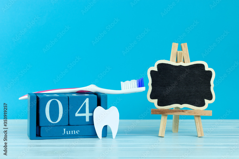 wooden calendar with the date of June 4, tooth, toothbrush and easel on ...