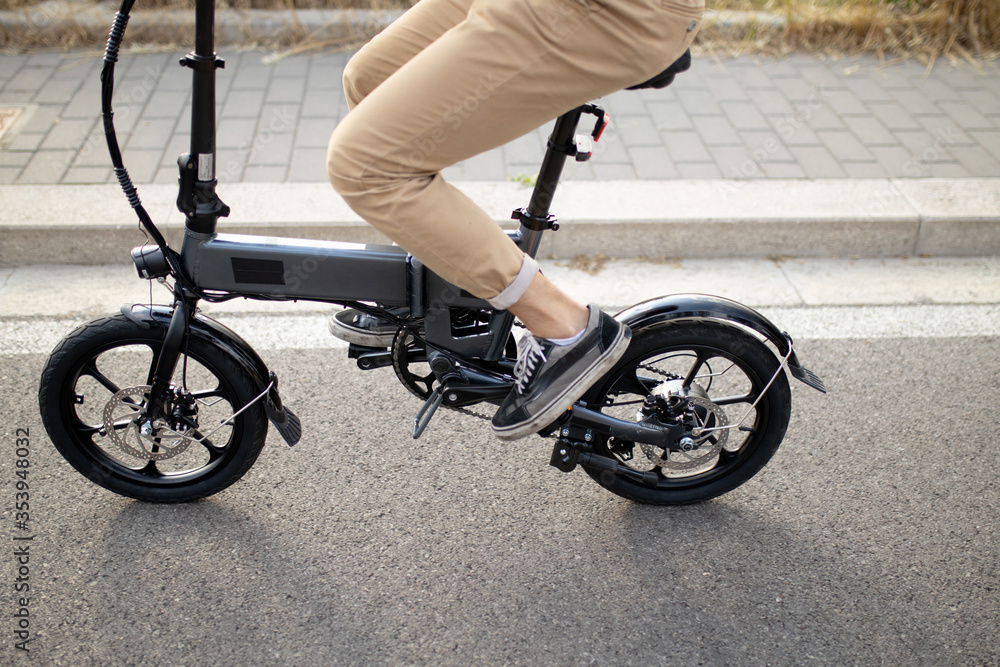 Caucasian attractive man rides his e - bike on the street to go to work ...