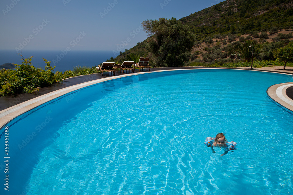 Little girl swimming in the swimming pool with a beautiful nature and ...