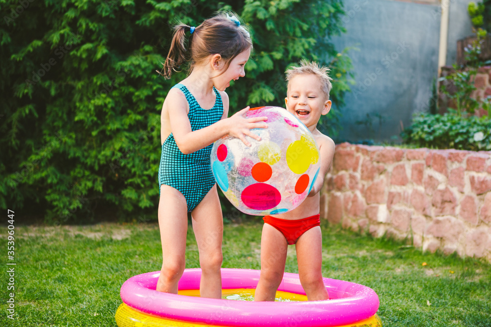 Two children with beach ball at swimming pool. Joyful kid playing in ...