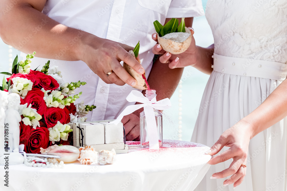 Bride and groom pouring colorful different colored sands into the ...