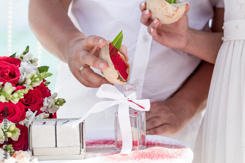 Bride and groom pouring colorful different colored sands into the ...
