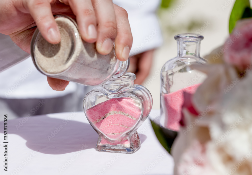 Bride and groom pouring colorful different colored sands into the ...