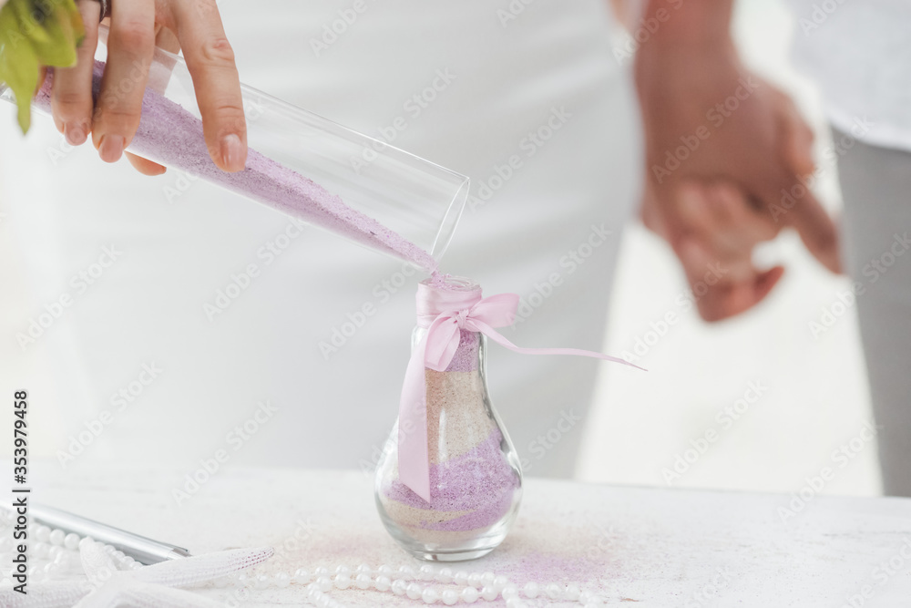 Bride and groom pouring colorful different colored sands into the ...