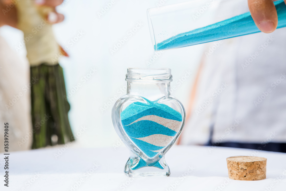 Bride and groom pouring colorful different colored sands into the ...